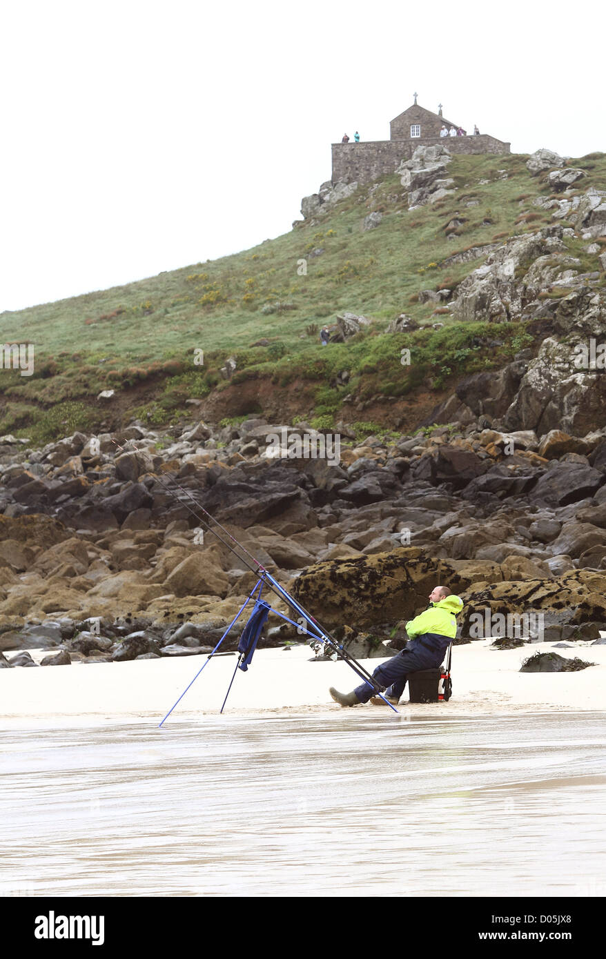 Man fishing beside the sea, on the beach at St Ives, Cornwall, England ...