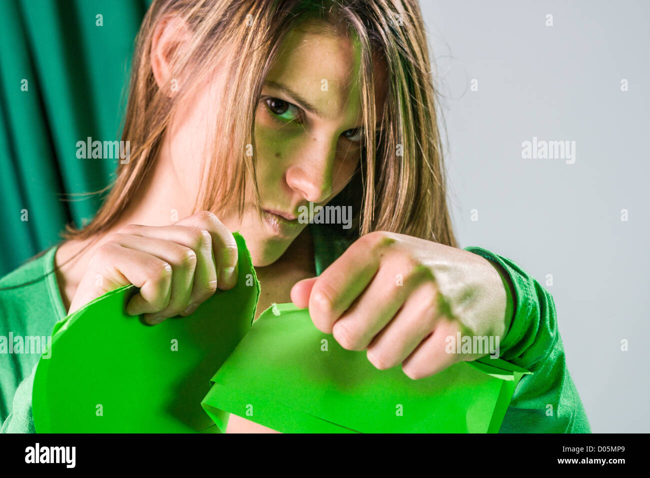 Young woman in green tearing a green sheet of paper Stock Photo - Alamy