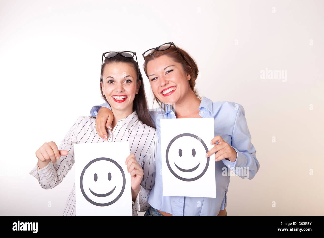 Portrait of a two young beautiful women holding smiley faces Stock ...