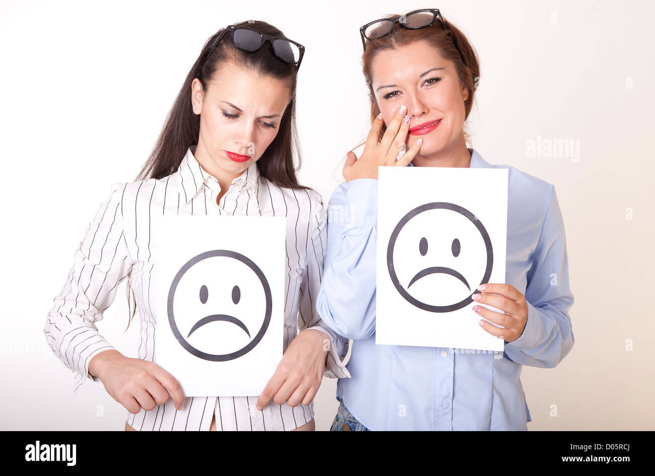 Portrait of a two young beautiful women holding sad smiley faces Stock ...