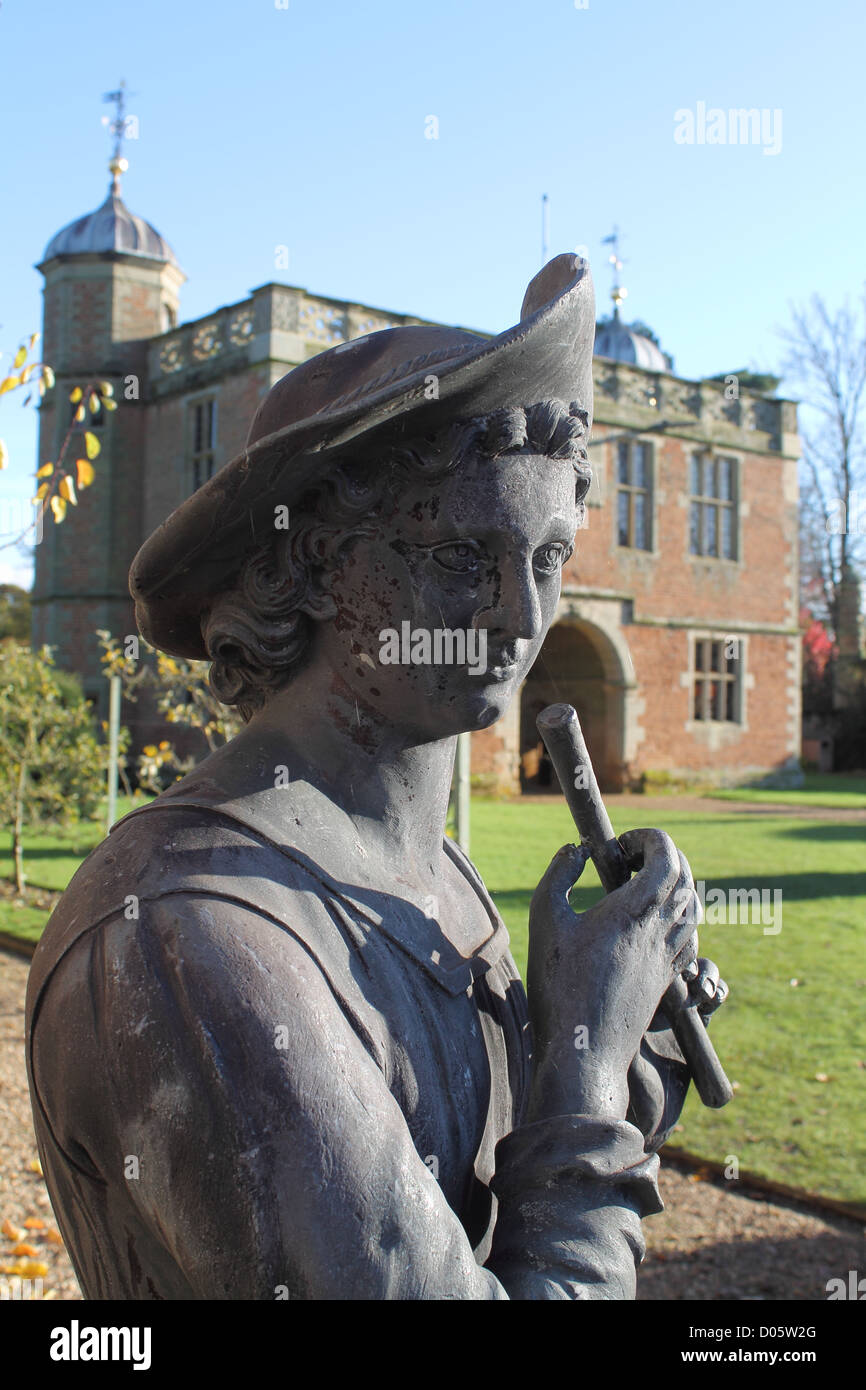 Garden statue of man with flute with Elizabethan gatehouse behind Stock ...