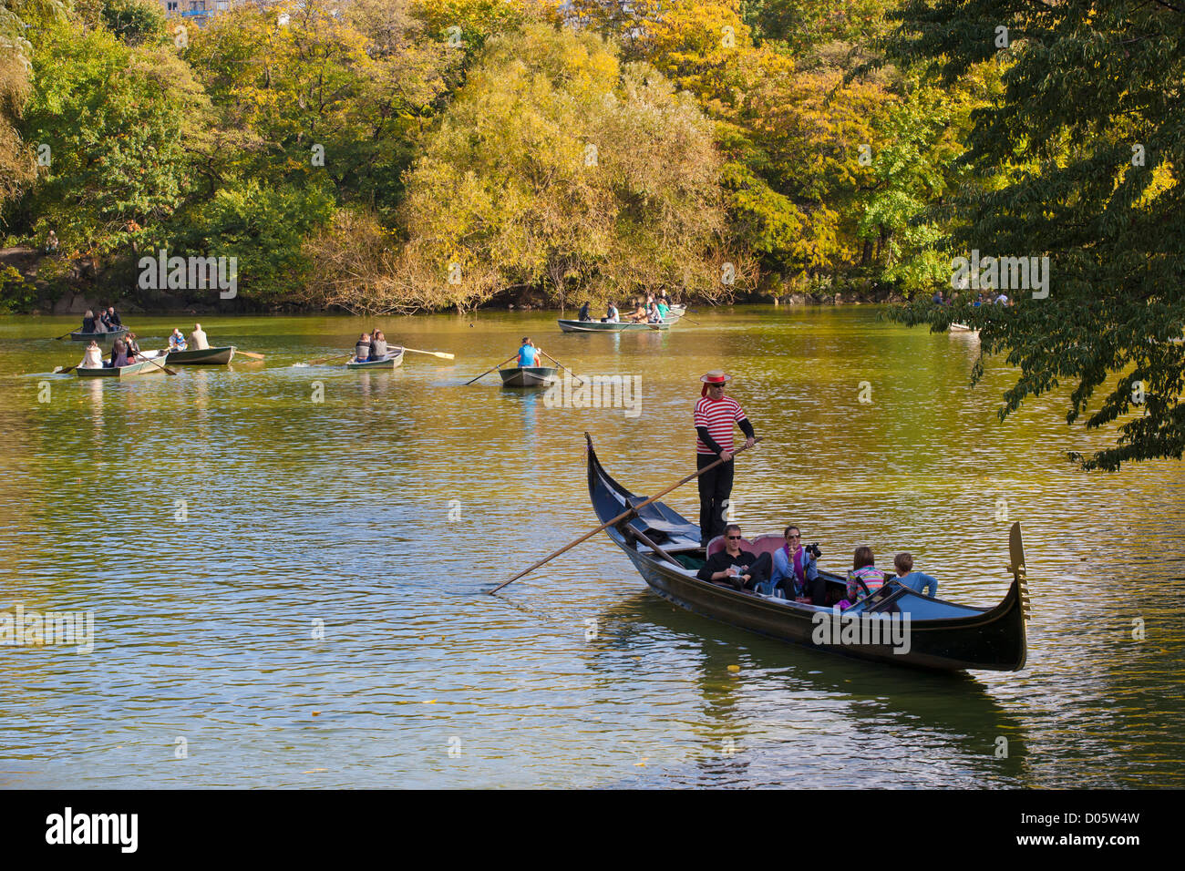 Gondolier rowing Gondola in the Central Park Lake with other row boats ...