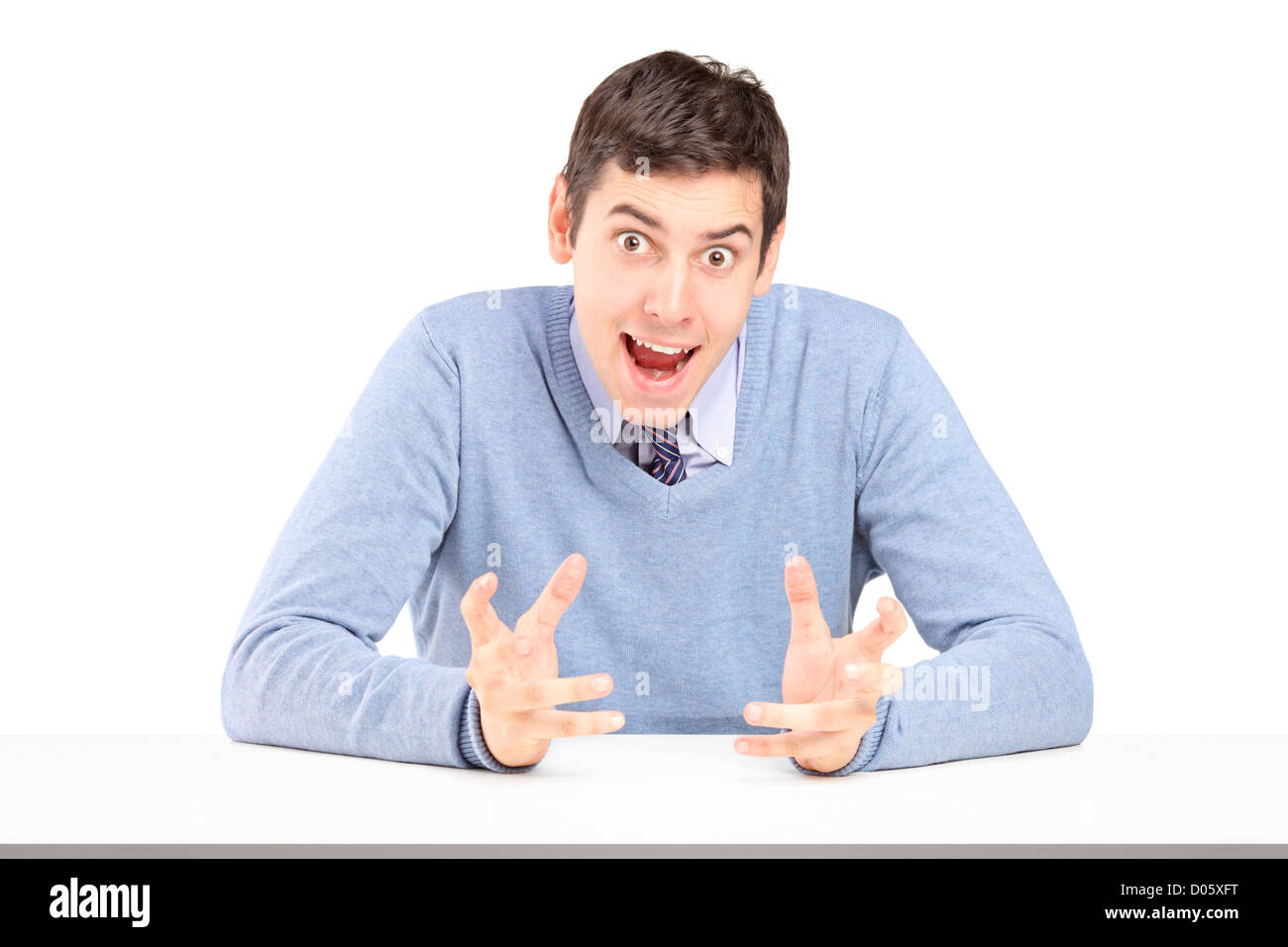 Angry young man sitting and gesturing with hands isolated on white ...