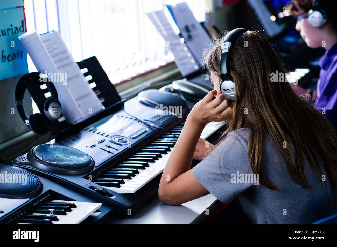 A girl playing electronic keyboard piano in a music class at a ...