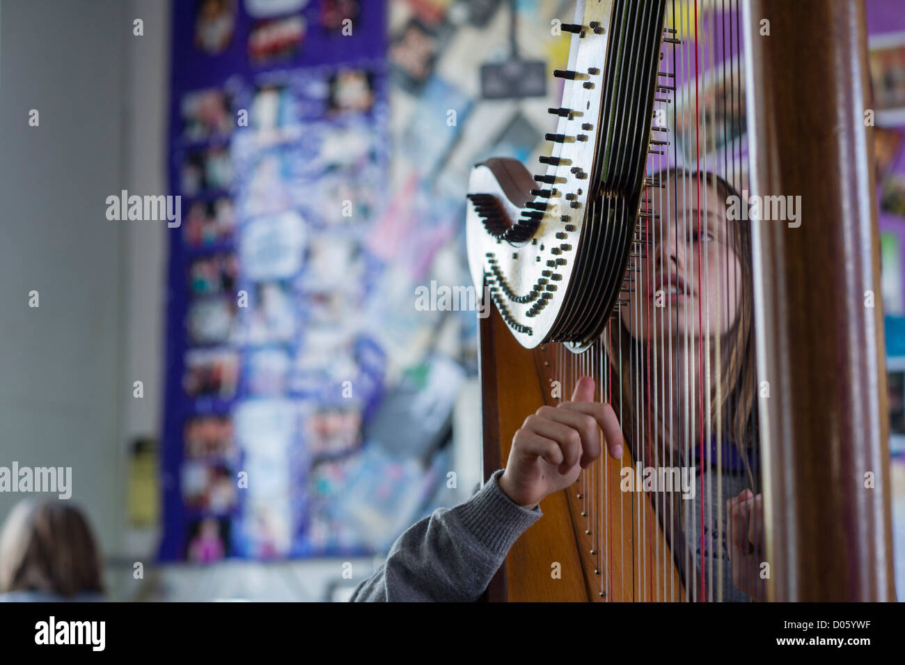 A girl playing the harp in a music class at a secondary comprehensive ...