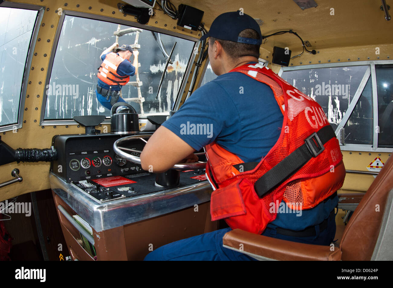 US Coast Guard captain watches as agent climbs a rope ladder on an oil ...