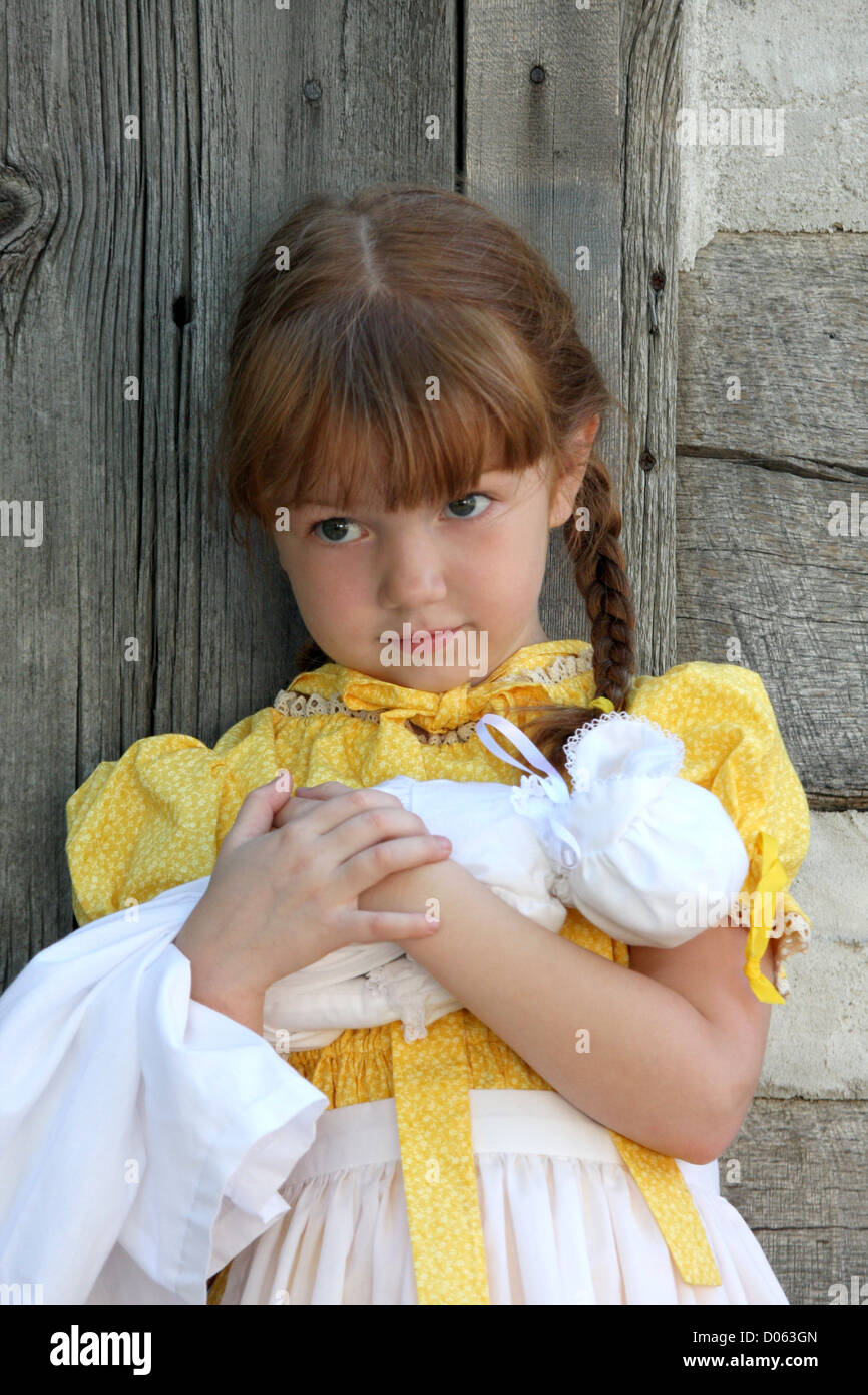 A young girl dressed in a prairie with a doll dress historical ...
