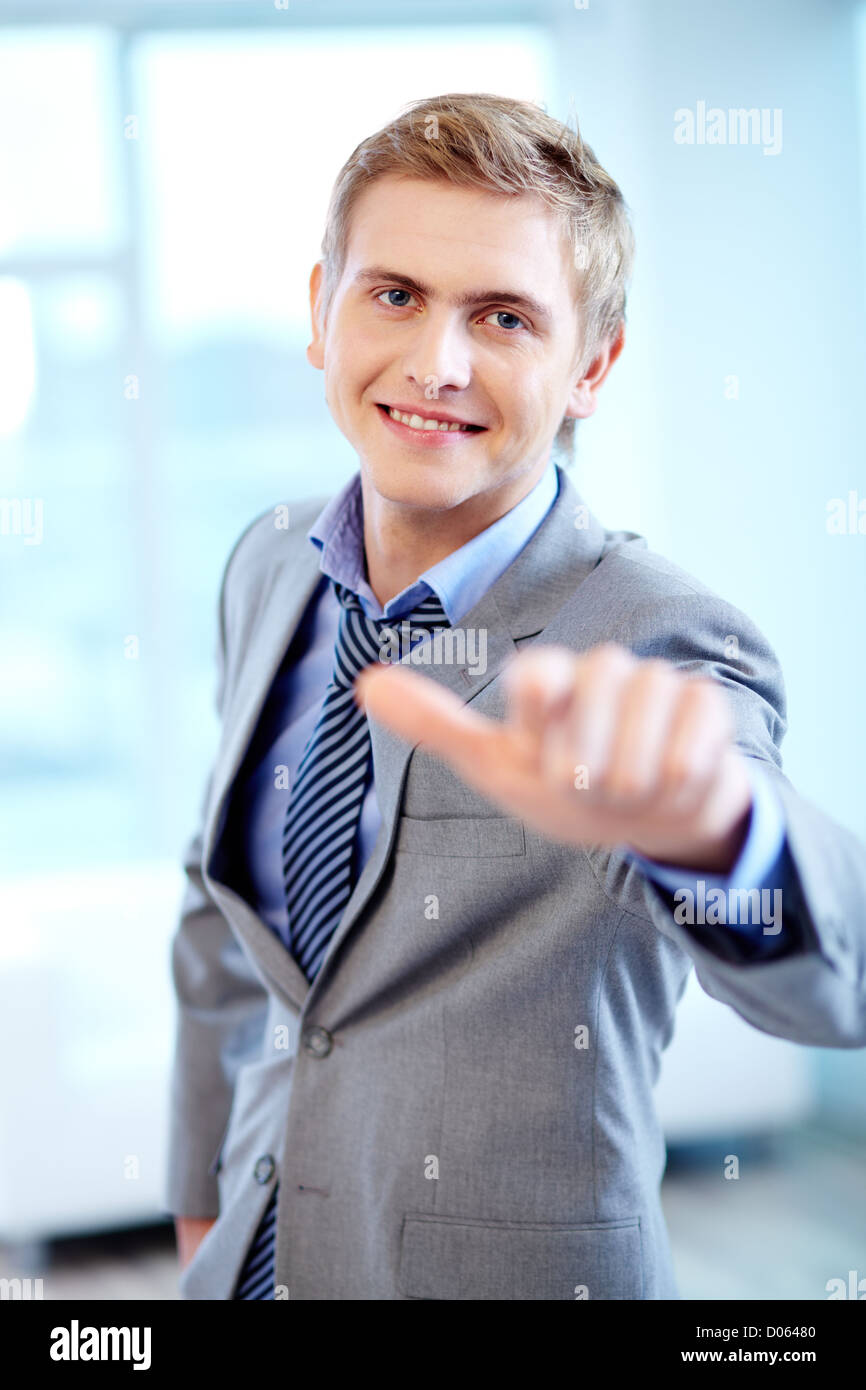 Portrait of cheerful businessman looking at camera while pointing at ...