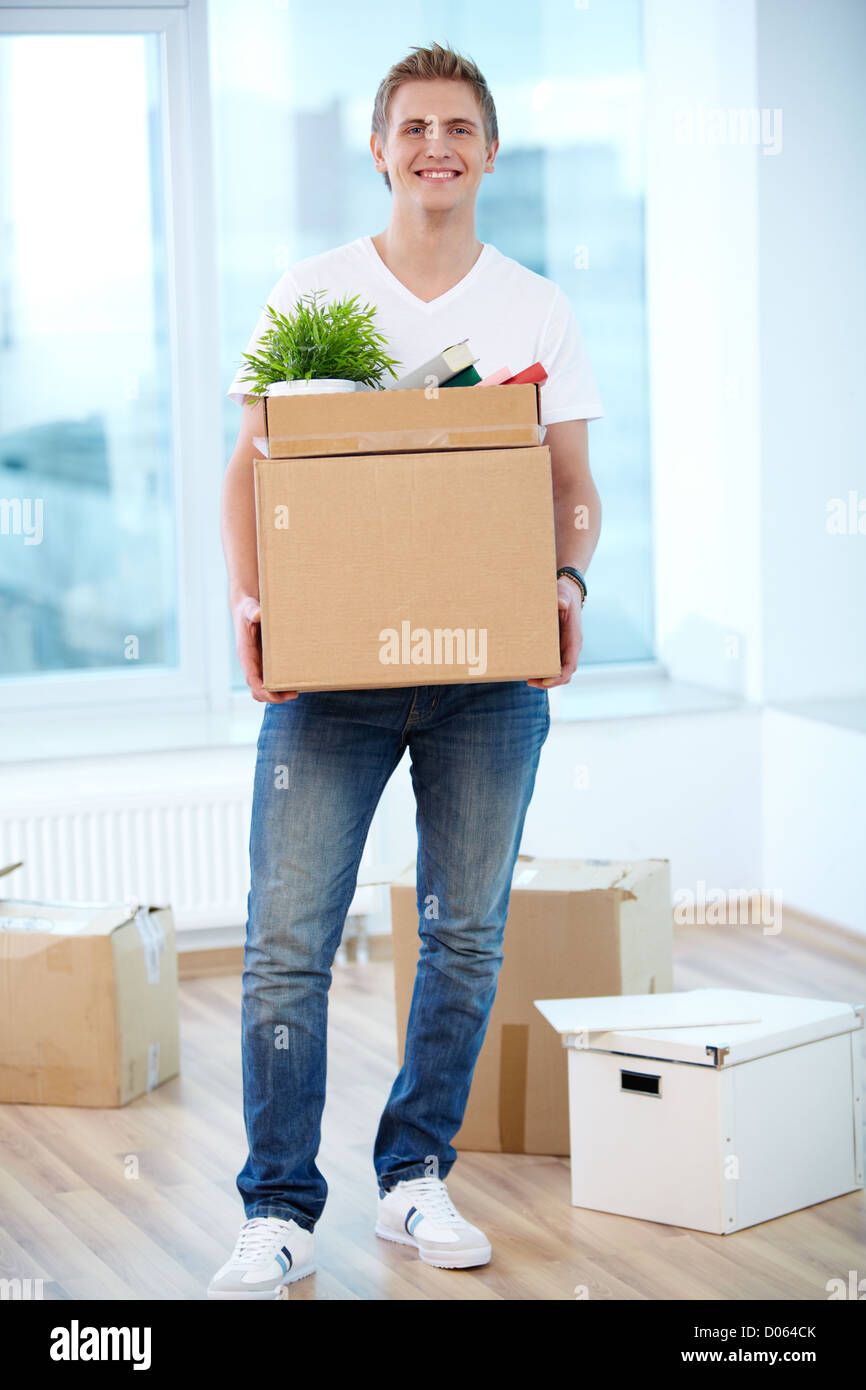 A young guy with boxes looking at camera in new flat Stock Photo - Alamy