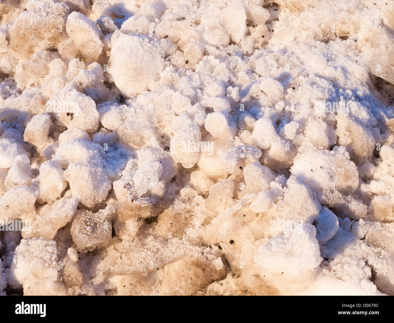 setting sun casting orange light on frost covered lumps of ice and snow ...
