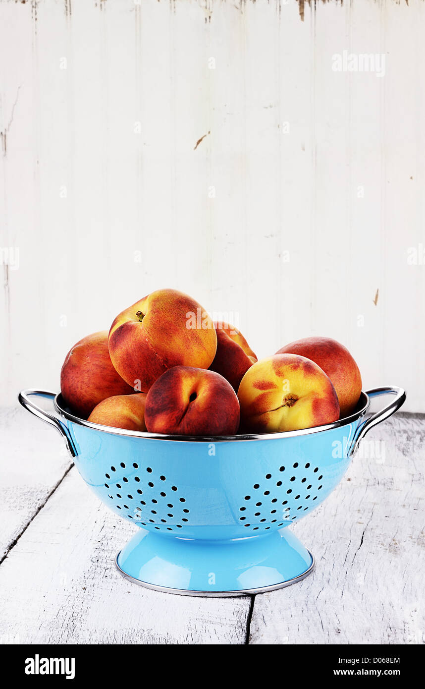 Blue colander filled with fresh peaches over a rustic background Stock ...