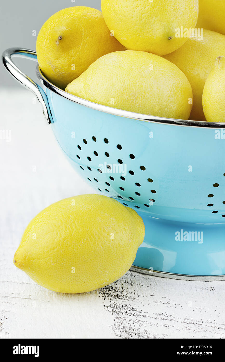Blue colander filled with fresh lemons over a rustic background Stock ...