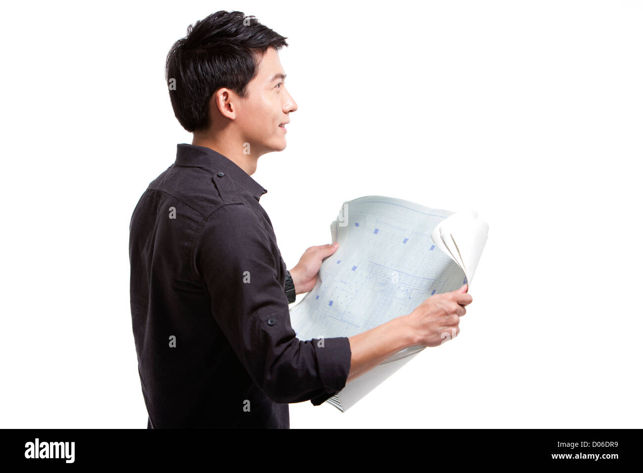 Young man with blueprint looking at view Stock Photo - Alamy