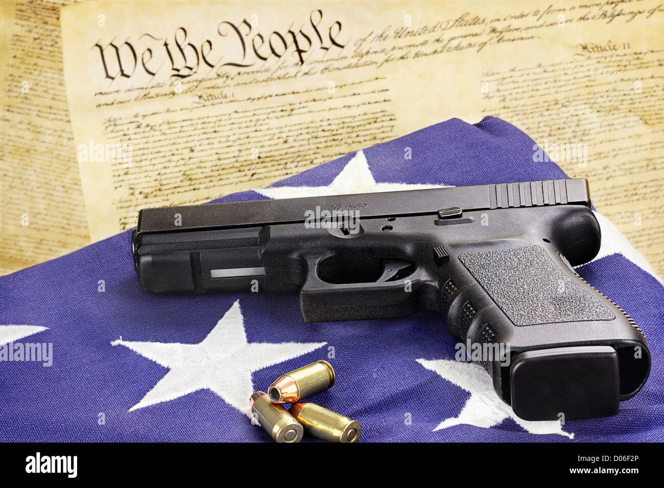 A 45 caliber handgun and ammunition resting on a folded flag against ...