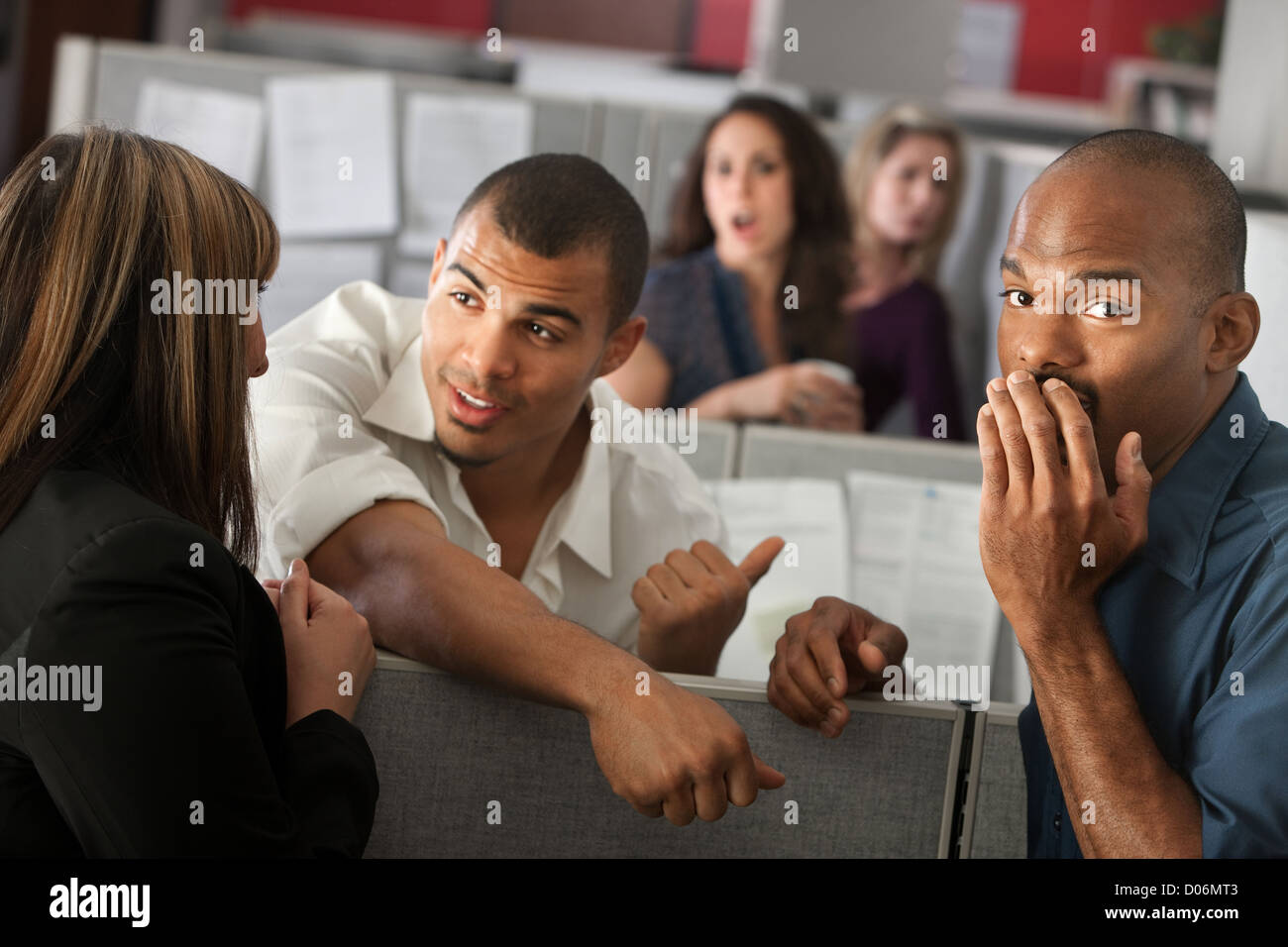 Embarrassed man with hand over mouth standing with coworkers Stock ...