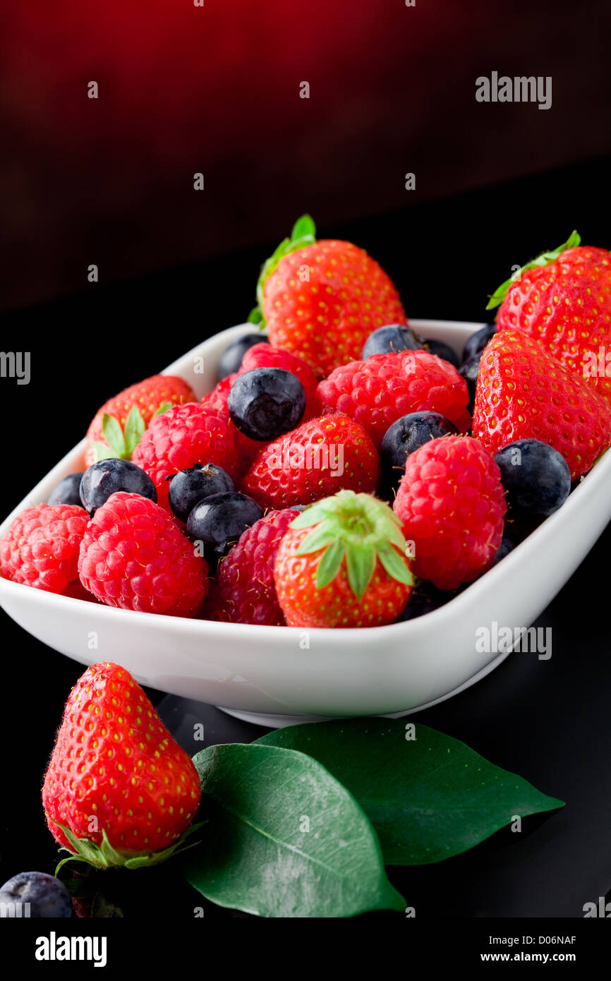photo of mixed fresh berries on red lighted background Stock Photo - Alamy