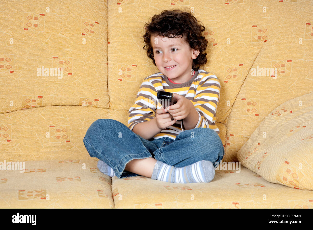 Beautiful child with the remote control of television sitting on the ...
