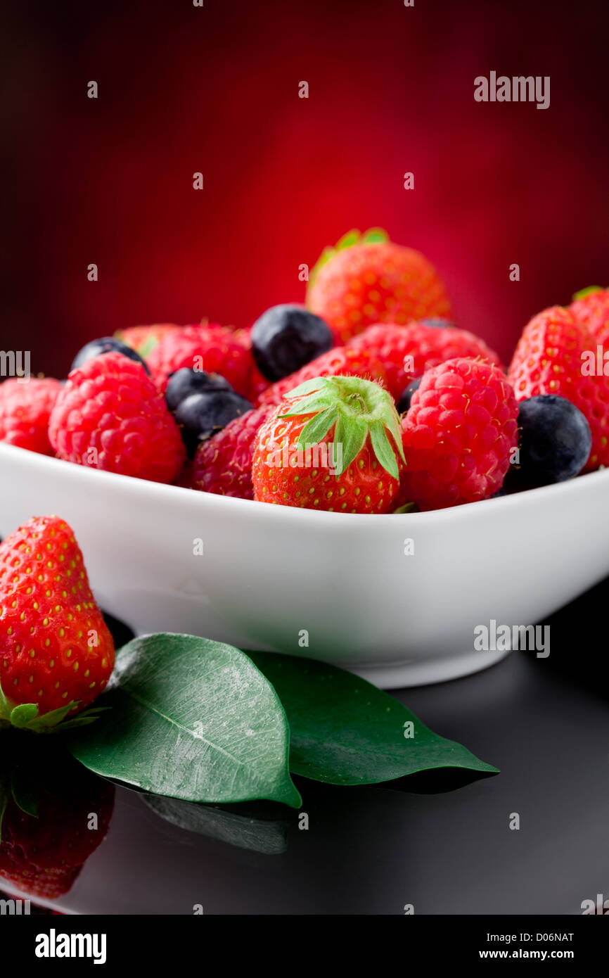 photo of mixed fresh berries on red lighted background Stock Photo - Alamy