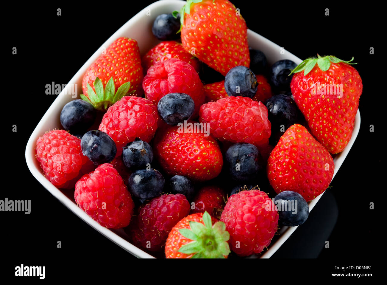photo of mixed fresh berries on red lighted background Stock Photo - Alamy