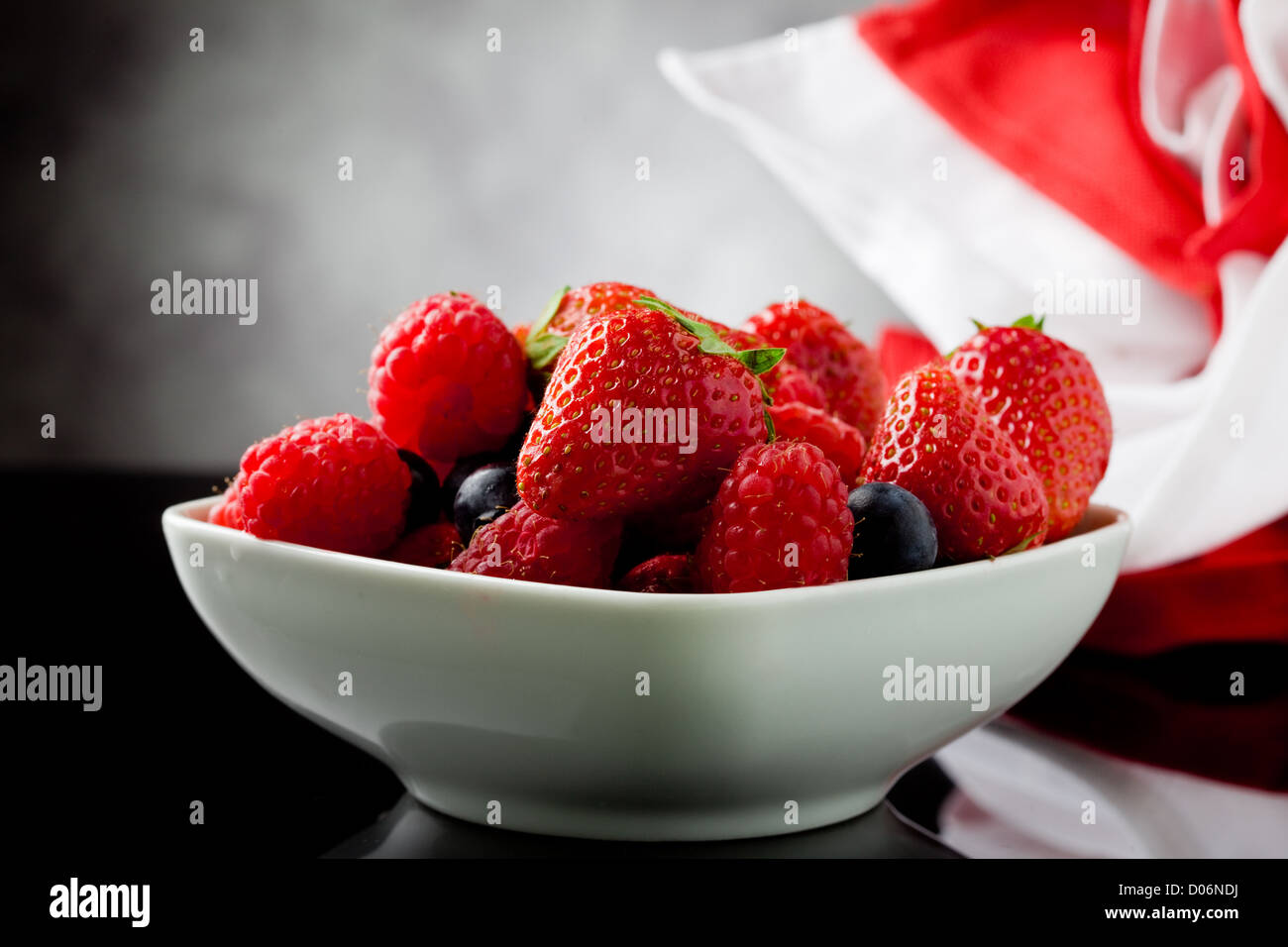photo of mixed fresh berries on grey lighted background Stock Photo - Alamy