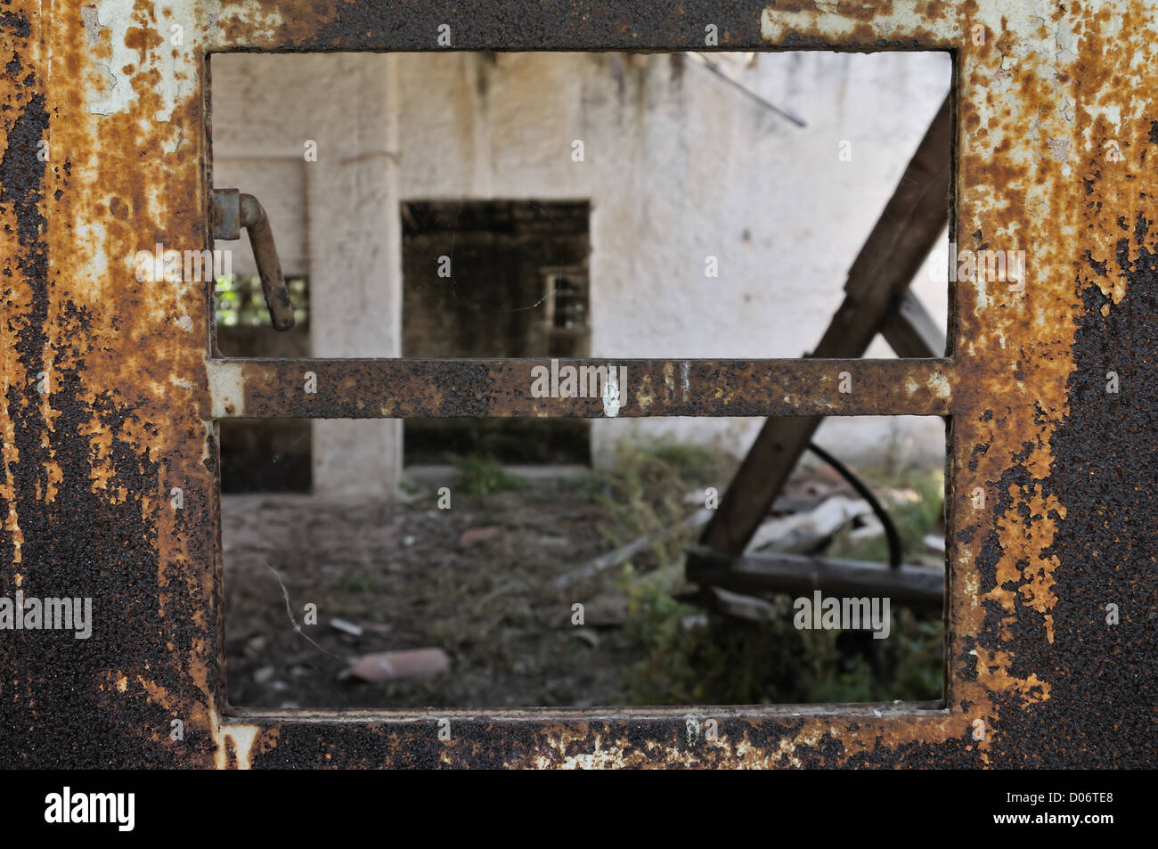 Rusty industrial door with chipped paint and view to abandoned ...