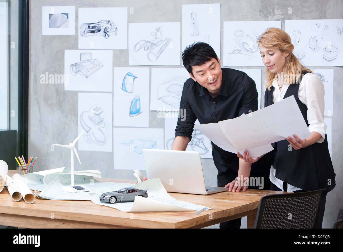 Designers studying blueprint in studio Stock Photo - Alamy