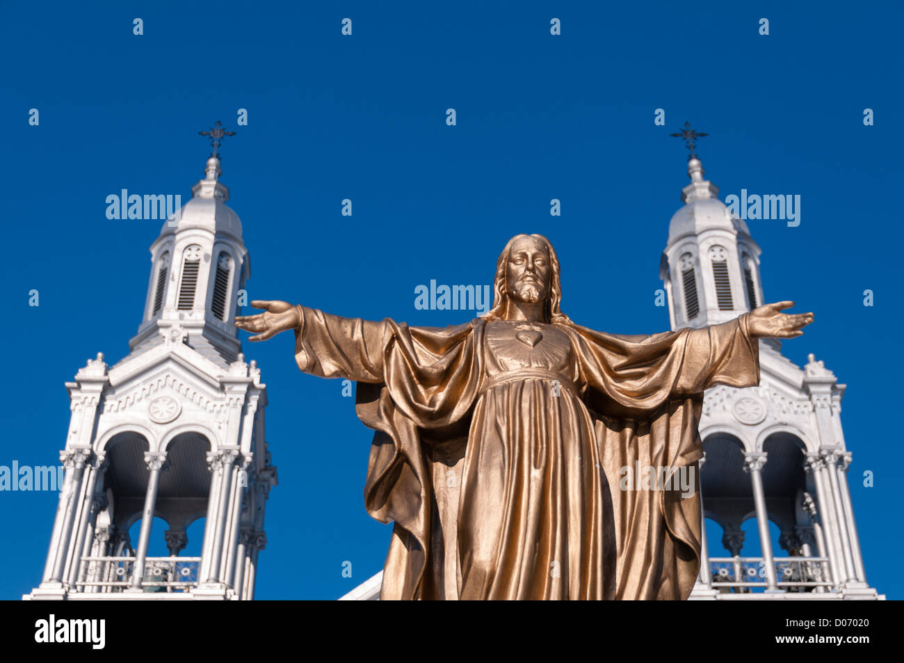 Gold statue of Jesus Christ in front of Catholic Church with vivid blue ...
