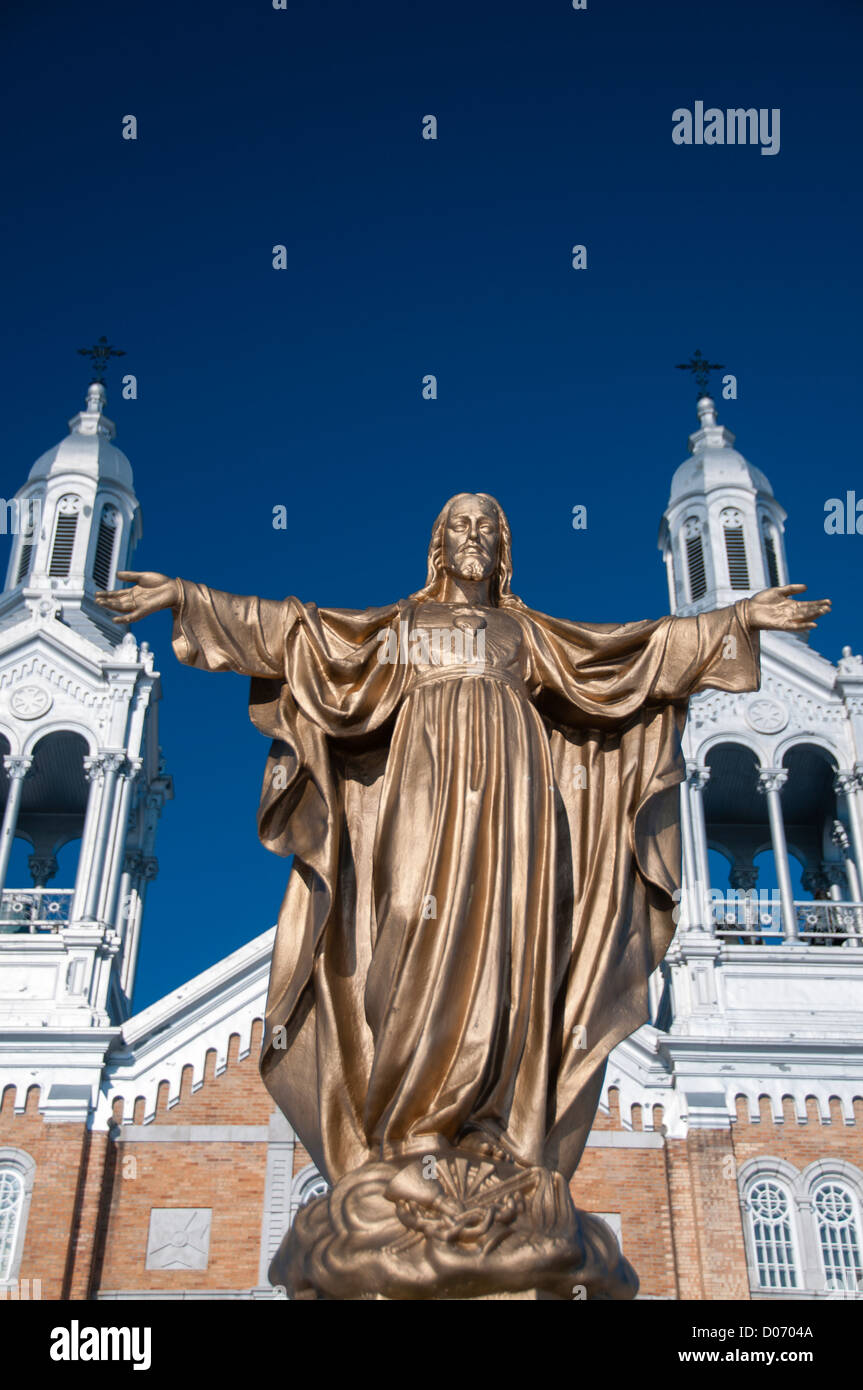 Gold statue of Jesus Christ in front of Catholic Church with vivid blue ...