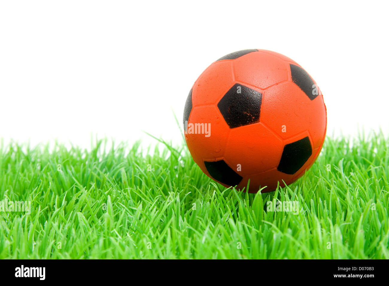Orange soccer ball on grass over white background Stock Photo - Alamy