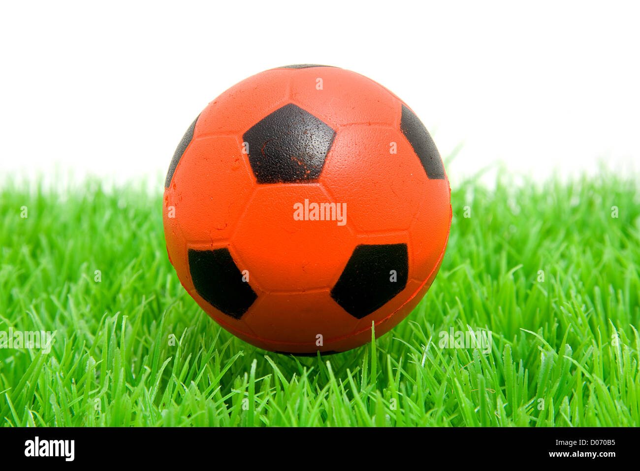 Orange soccer ball on grass over white background Stock Photo - Alamy