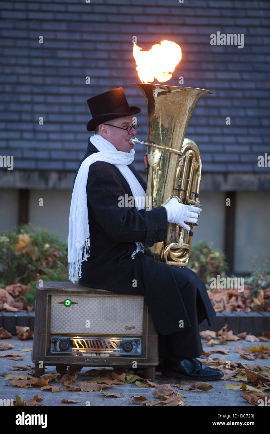 A street performer playing a brass tuba with flames appearing from the ...