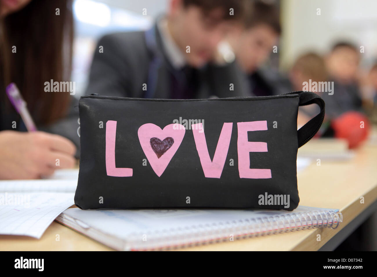 Pencil case on school desk, table out of focus children behind ...