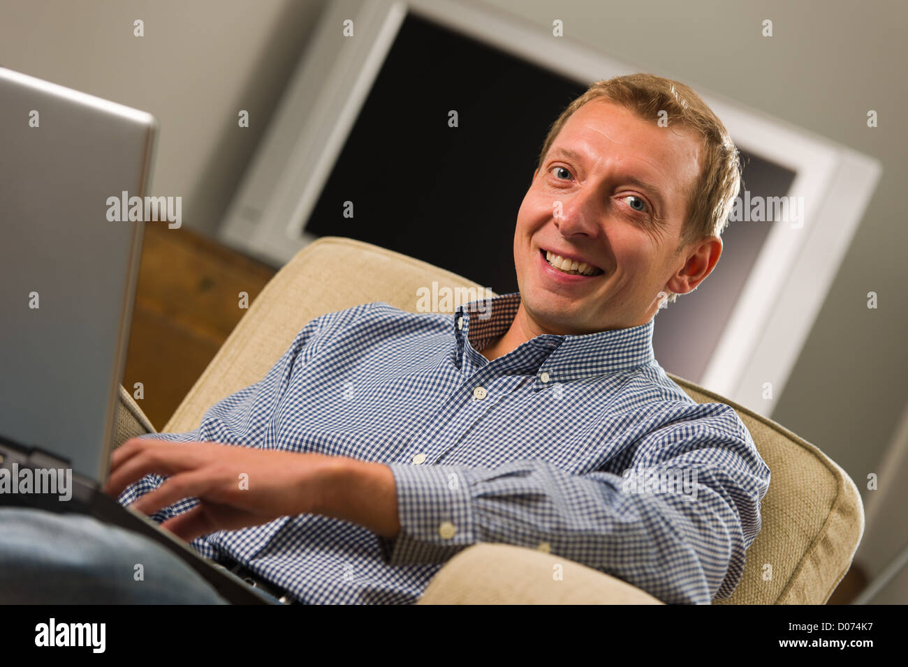 Man sitting on the armchair and use his laptop Stock Photo - Alamy