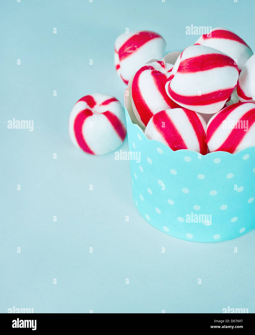 Striped peppermint candy in a cupcake, on pastel colored blue ...