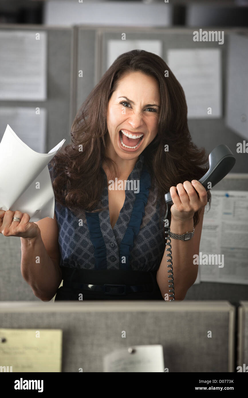 Screaming woman with phone and notes in office cubicle Stock Photo - Alamy