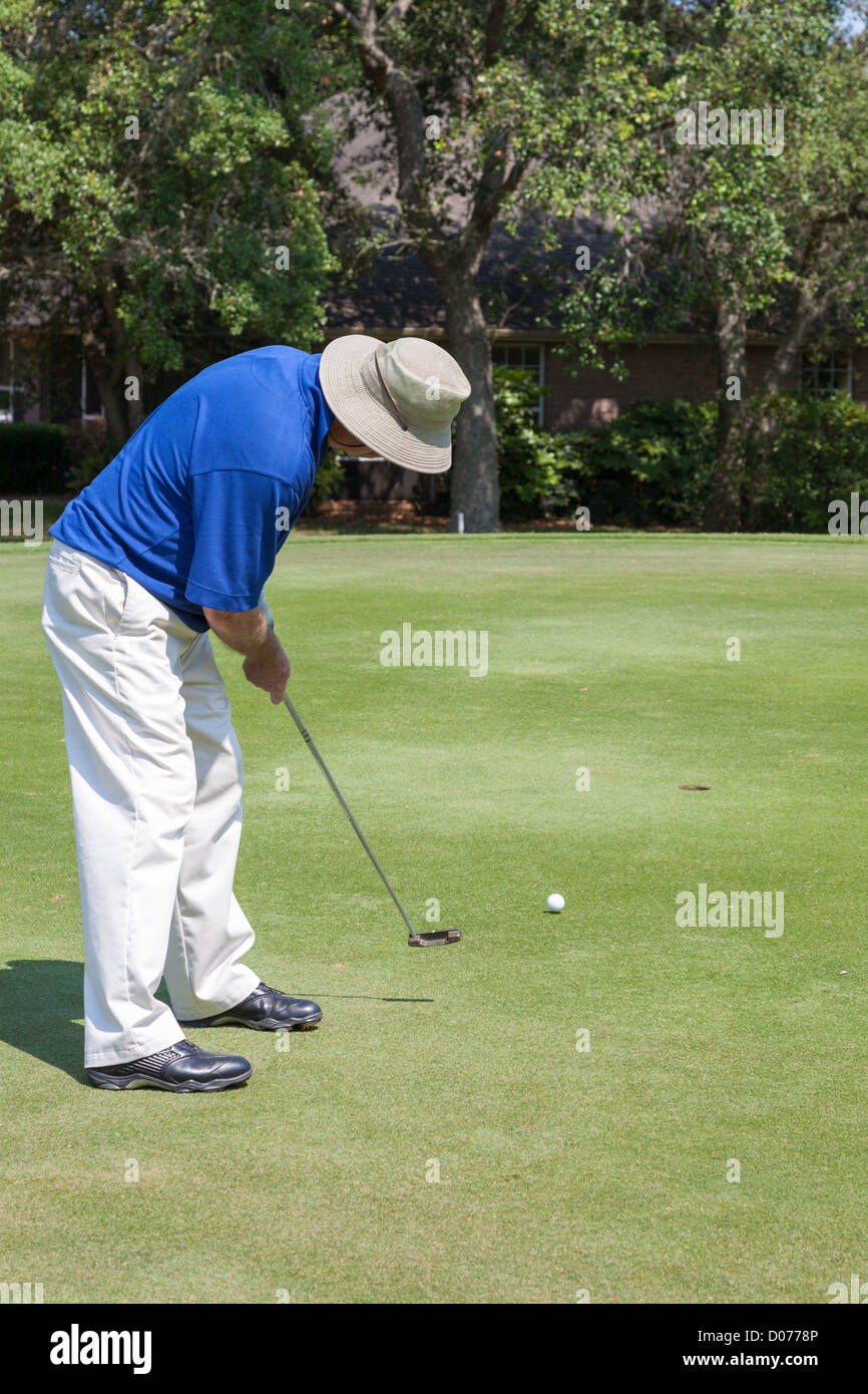 Senior man with hat putting on green at golf course Stock Photo - Alamy
