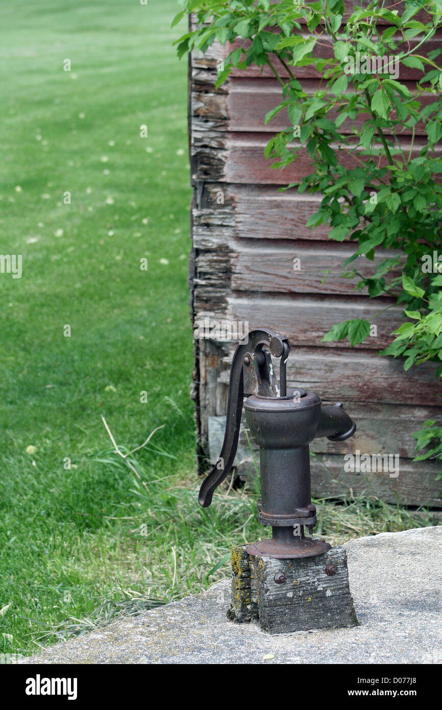 An antique cast iron water pump on a concrete cistern in spring on a ...