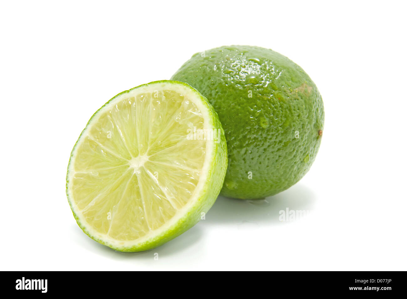 fresh juicy green lime, one whole and one half, with waterdrops ...