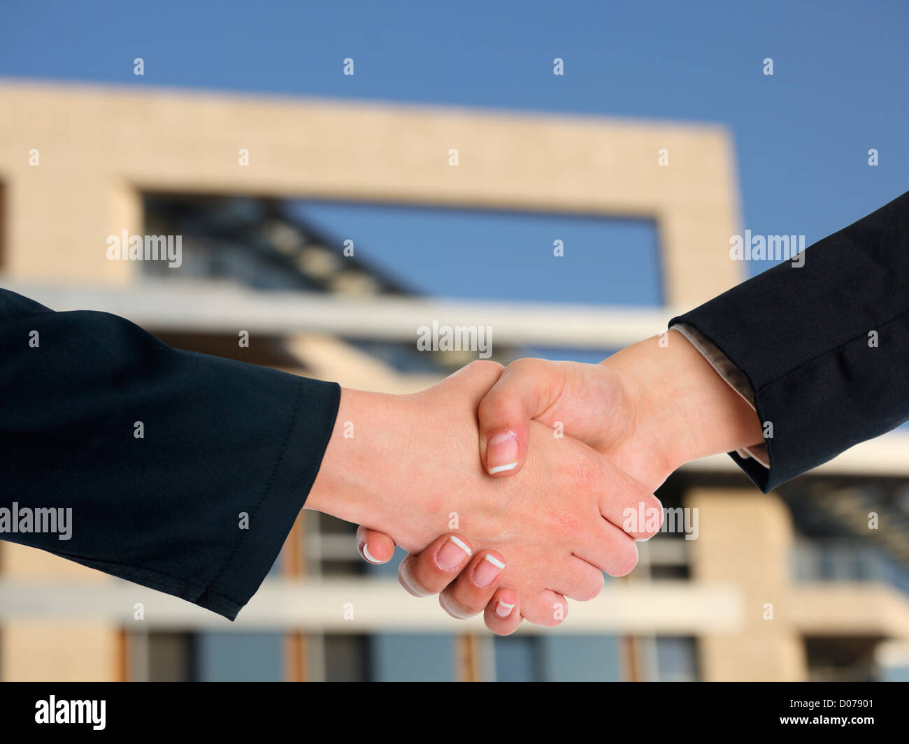 Handshake Handshaking and blured building in background Stock Photo - Alamy