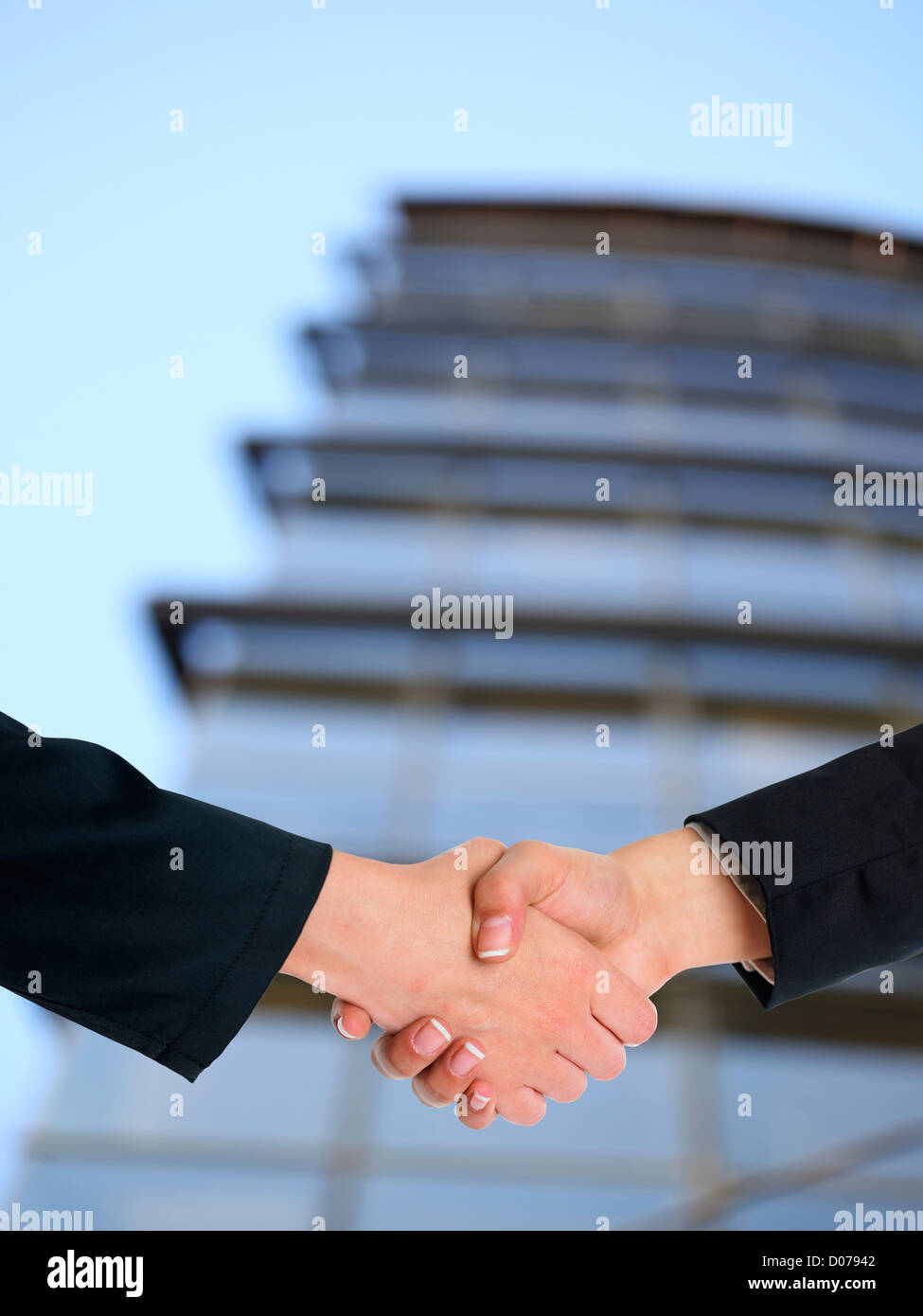 Handshake Handshaking and blured building in background Stock Photo - Alamy