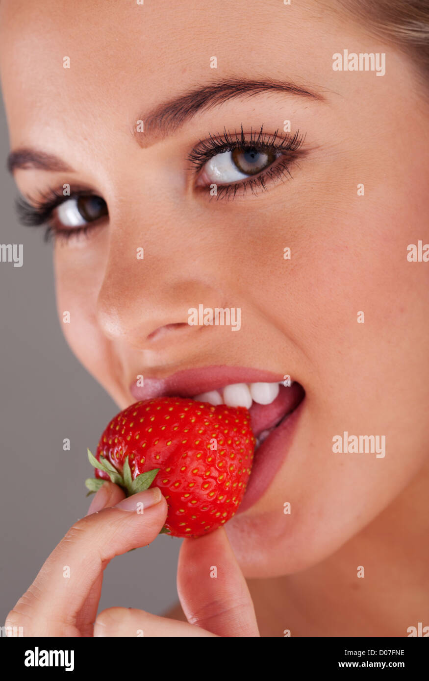 Happy young woman eating mellow strawberry Stock Photo - Alamy