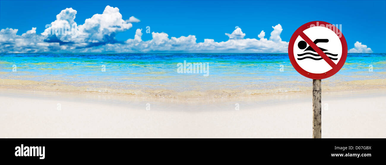 Tropical beach with sign warning to not swim Stock Photo - Alamy