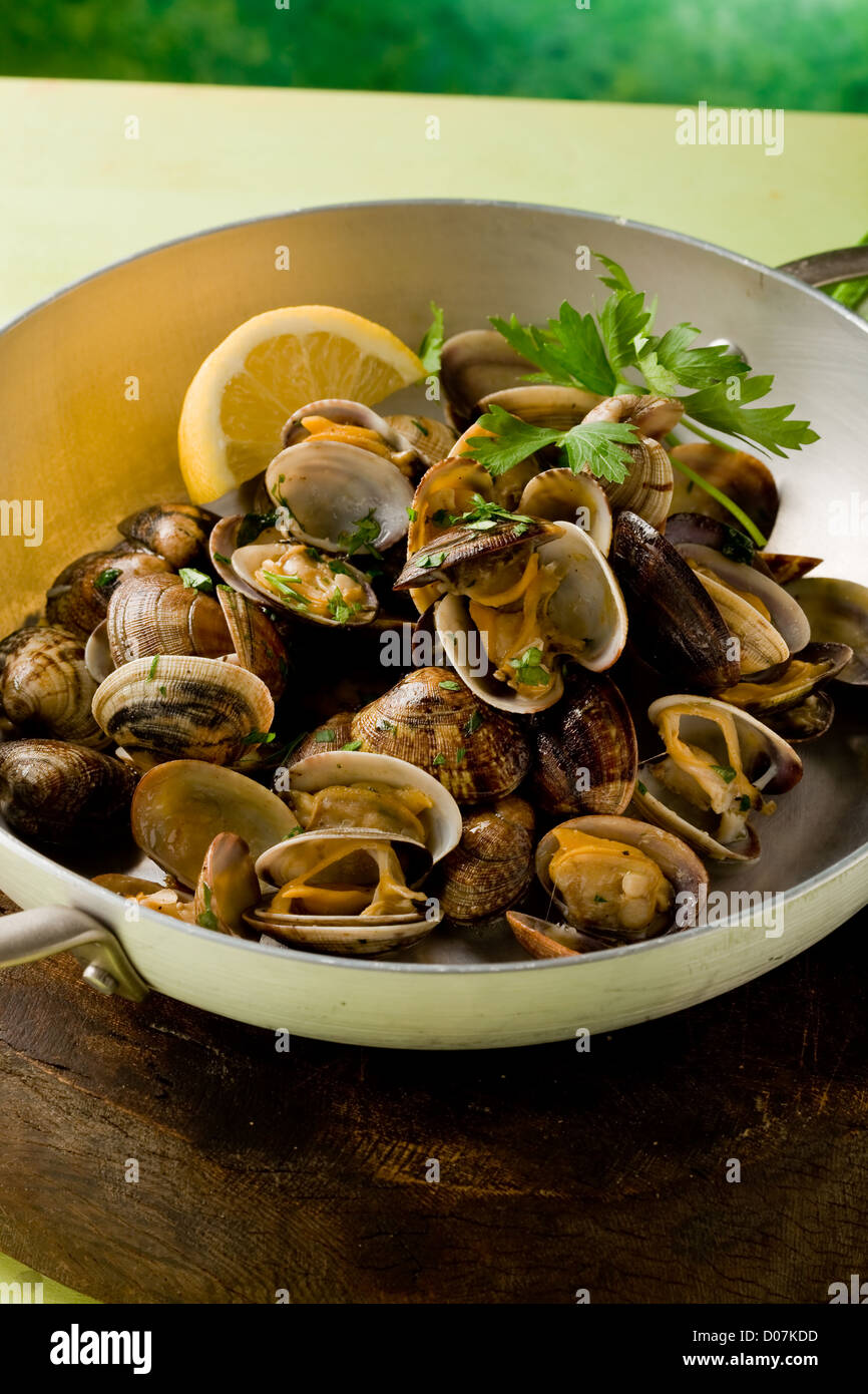 photo of delicious clams inside a pan in front of a greeb background ...