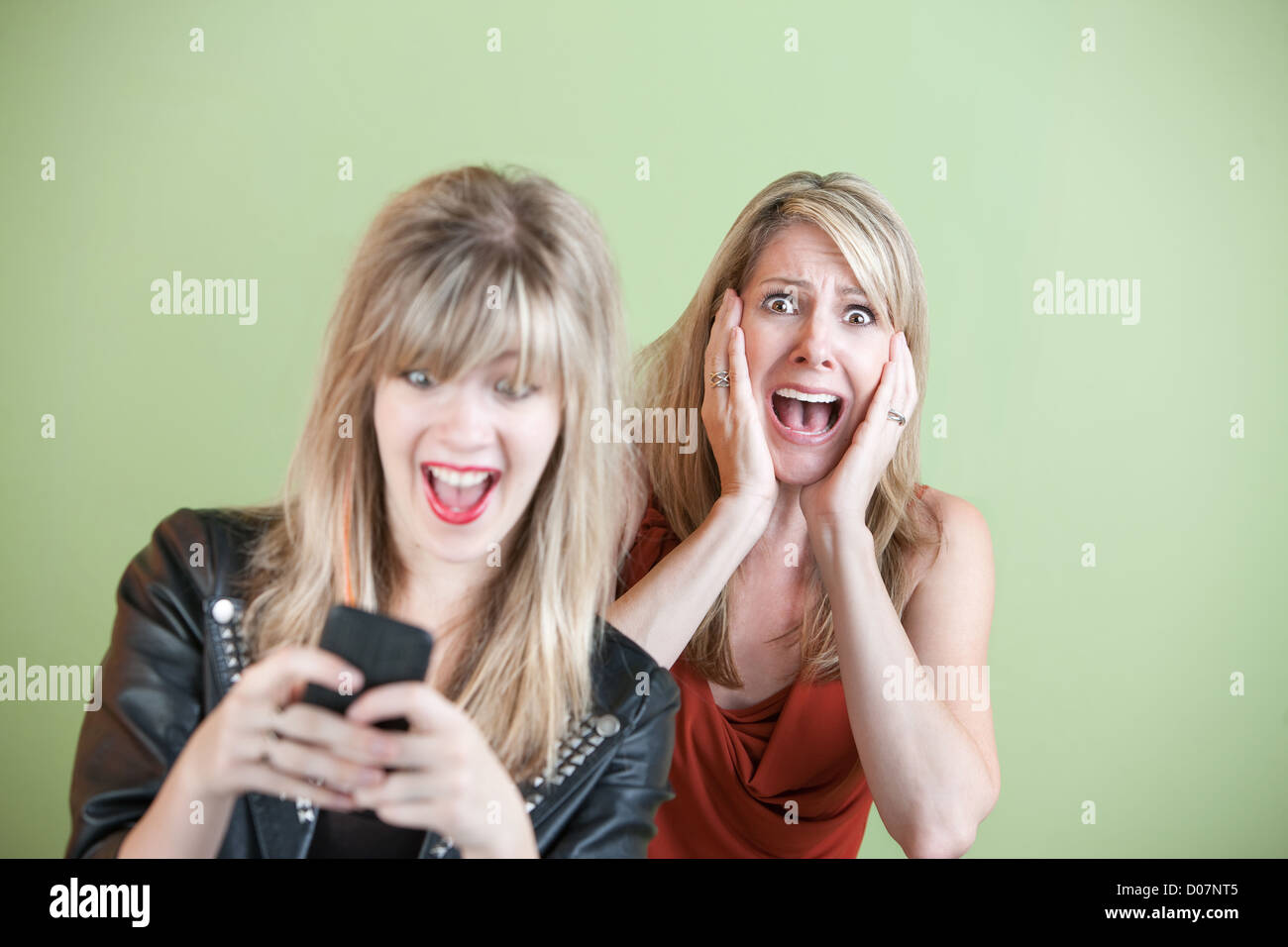 Excited daughter texting with shocked mom behind her over green ...