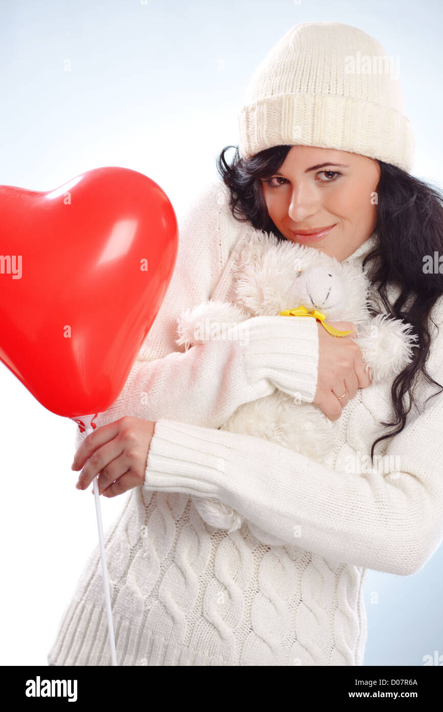 Cute young woman wearing warm winter clothing and holding heart posing ...