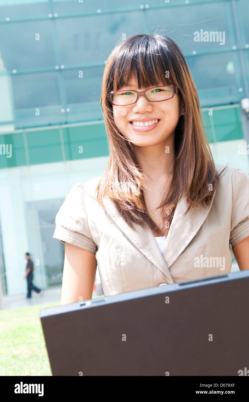 Asian student using laptop outside modern building Stock Photo - Alamy
