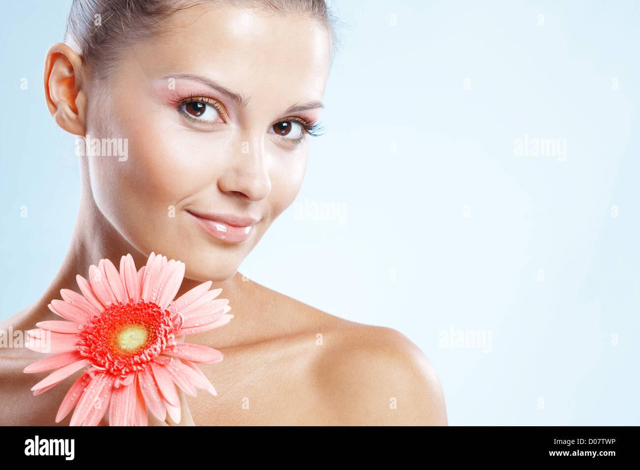 Beautiful female with fresh makeup and clear skin holding pink daisy ...