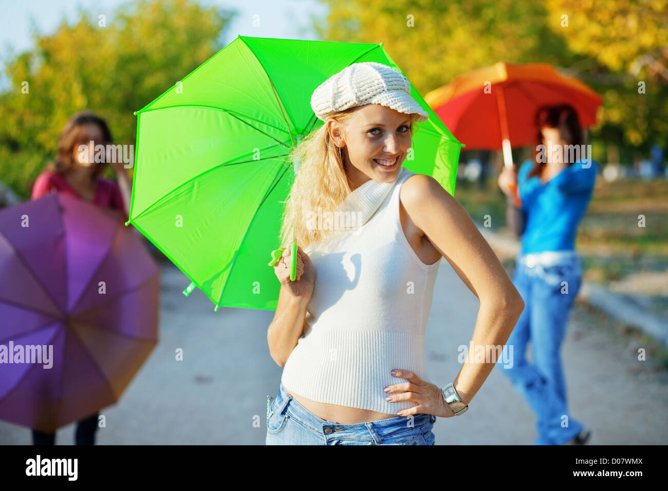 Three fashion teenage girls posing with colorful umbrellas in autumn ...
