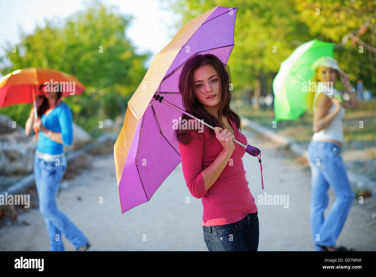 Three fashion teenage girls posing with colorful umbrellas in autumn ...