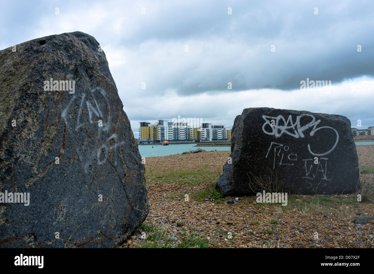 Graffiti on rocks with the Eastbourne sovereign harbour development in ...